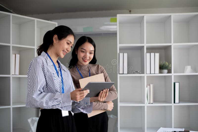 Two Asian Businesswomen Discussing Work Using a Tablet in a Modern ...