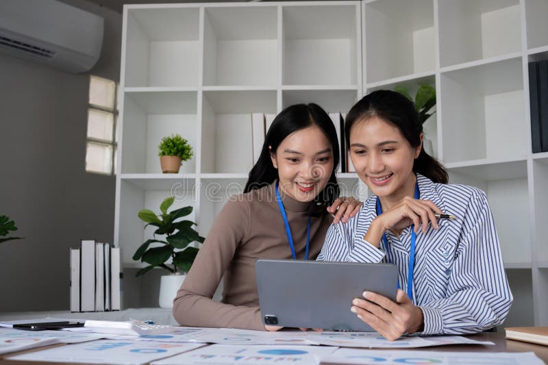 Two Asian Businesswomen Discussing Work Using a Tablet in a Modern ...