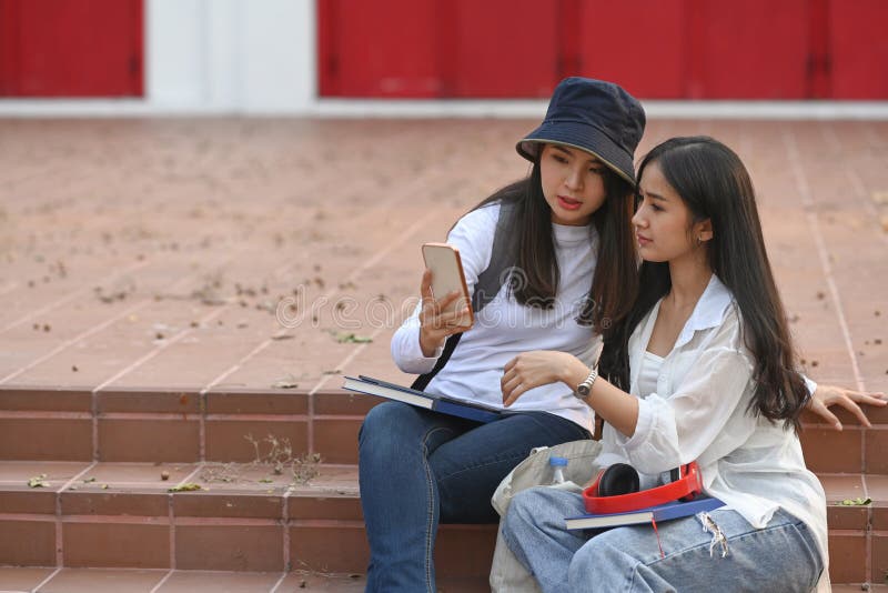 Two Female Students Using Mobile Phone and Resting after Their Class at ...