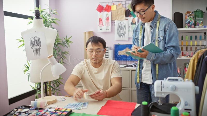 Two Asian Men Collaborating in a Tailor Shop, with One Designing and ...