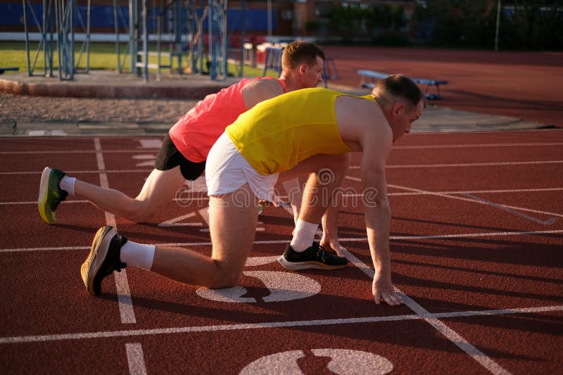 Two Athletes in the Stadium are Preparing To Run from a Low Start Stock ...