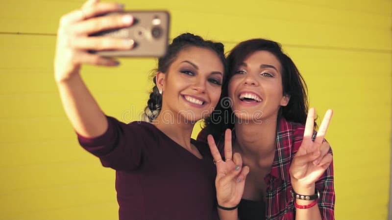 Two Attractive Women Posing While Taking Selfie And Showing Peace Sign