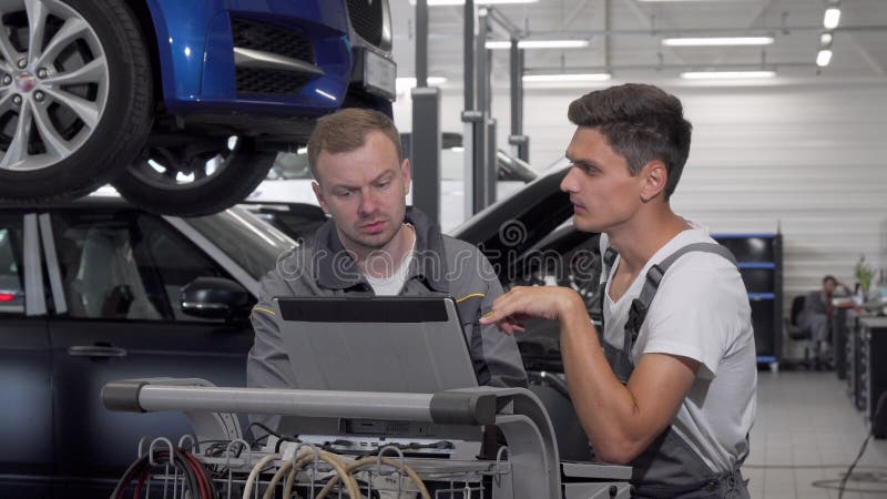 Two Auto Mechanics Talking at the Garage Using Laptop in Car ...