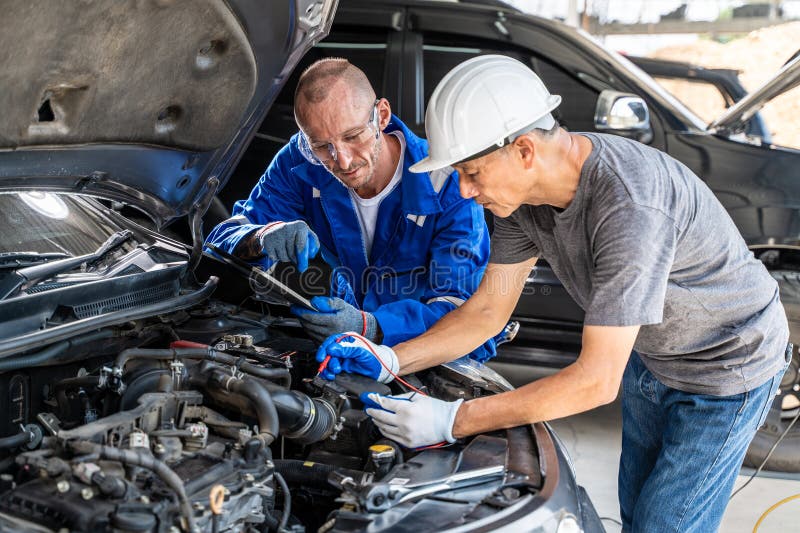 Two Auto Mechanics Using a Computer Measuring Device To Check the Car ...