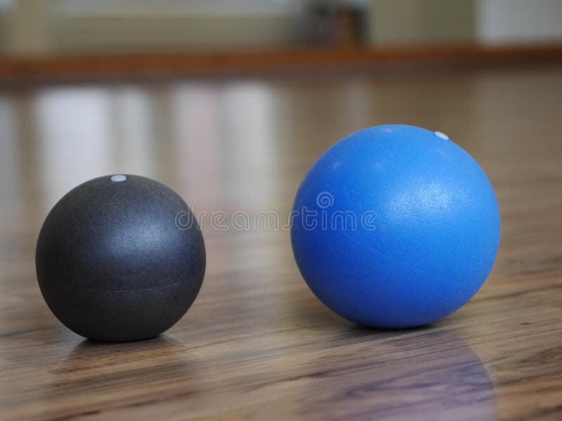 Two Balls, One Blue and One Black, are Sitting on a Wooden Floor Stock ...