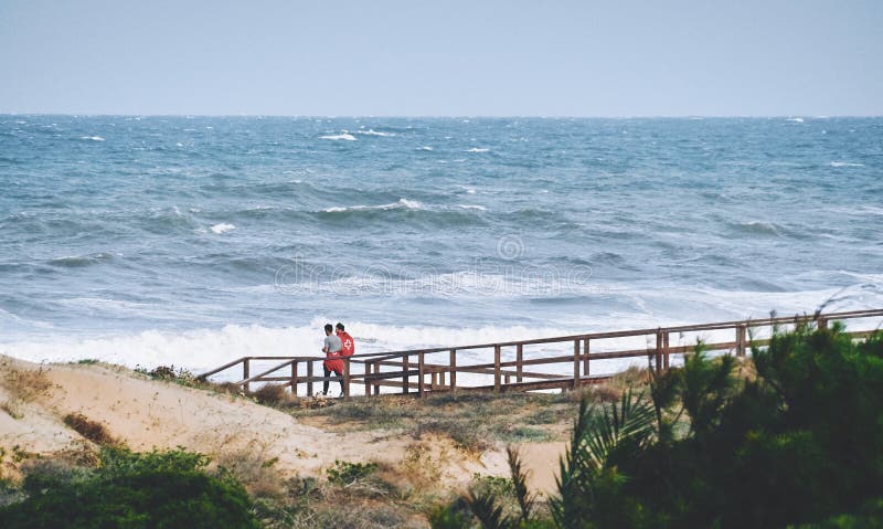 Two Beach Watchers Watching the Sea with Waves Stock Image - Image of ...