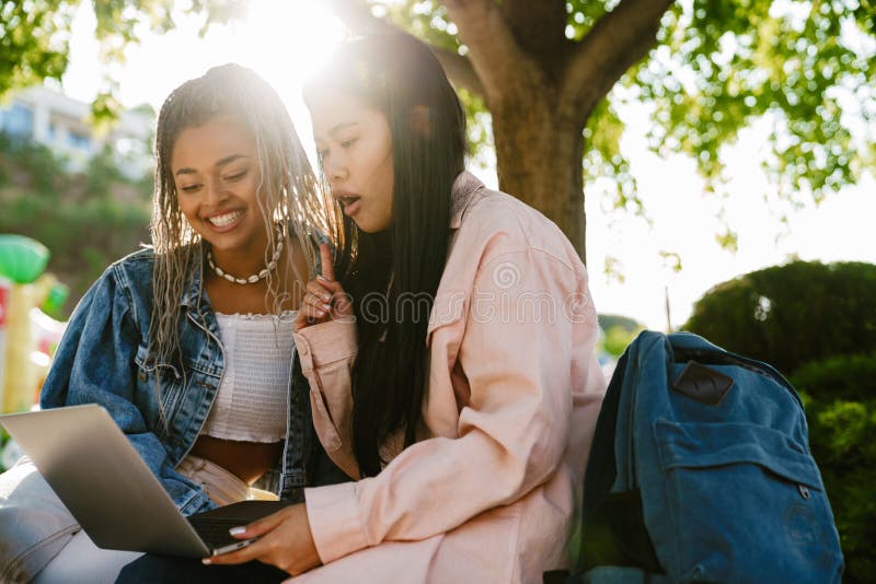 Two Beautiful Women Using Laptop while Sitting in Park Stock Photo ...