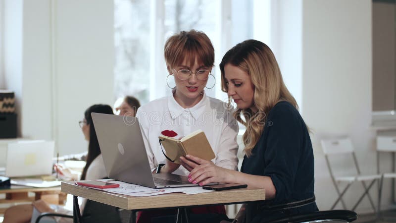 Two Beautiful Young Female Managers Working Together with Laptop and ...