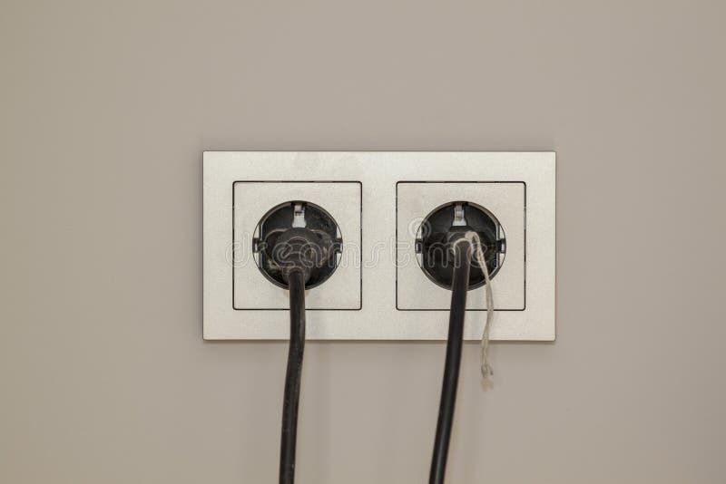 Two Black Plugs are Plugged into Double Electrical Outlet with Frame ...