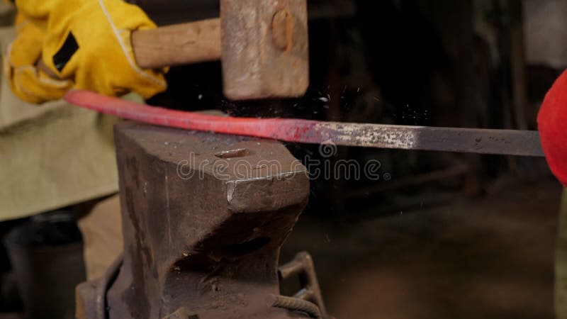 Two Blacksmiths are Beating with Hammers on Hot Metal on an Anvil in ...
