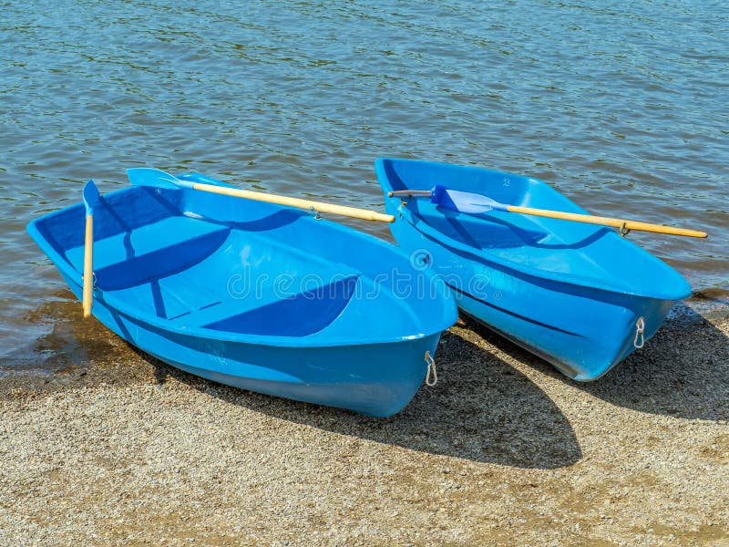 Two Blue Plastic Boats with Oars Pulled Ashore Stock Image - Image of ...