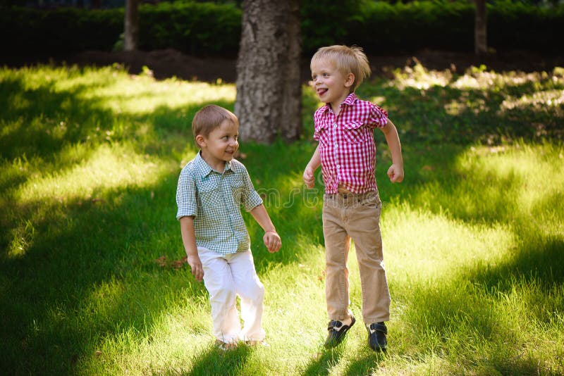 Two Boys Brothers Playing and Jumping Outdoors in a Park. Stock Photo ...