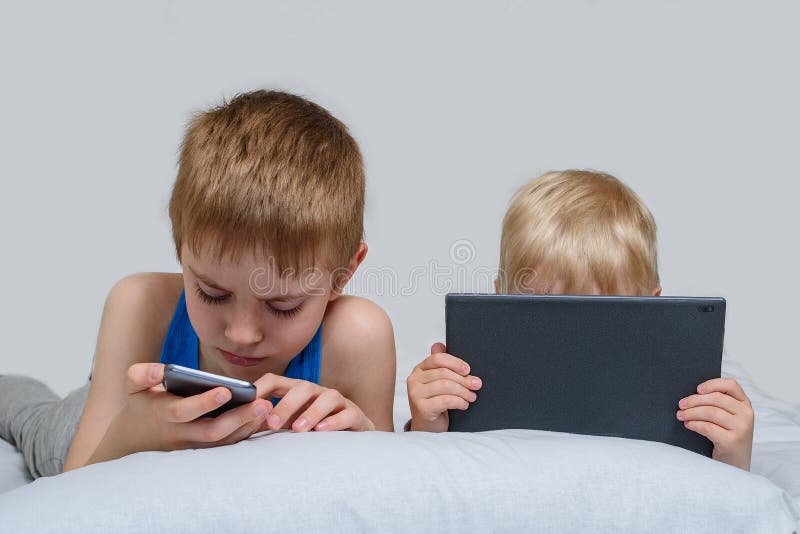 Two Boys with Gadgets are Lying in Bed. Children Use Smart Phone and ...