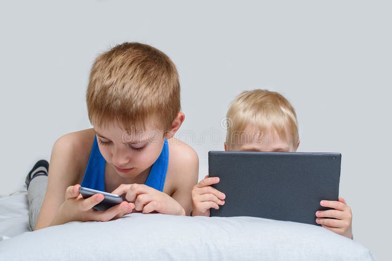 Two Boys with Gadgets are Lying in Bed. Children Use Smart Phone and ...