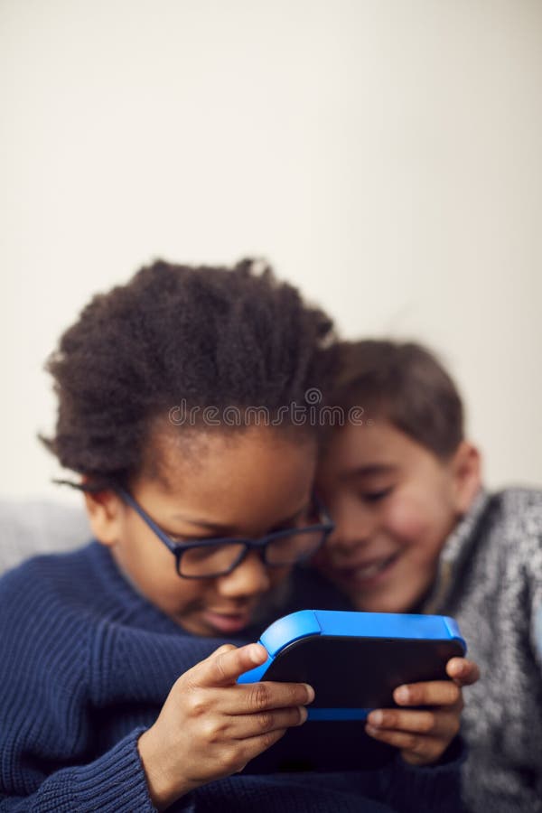 Group of Young Boys Gaming Together on Hand Held Devices at Home Stock ...