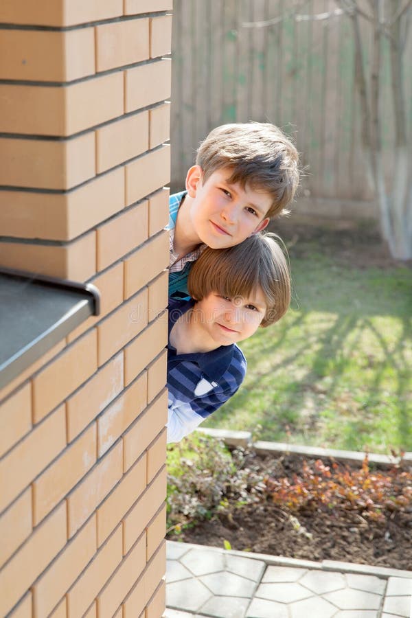 Two Boys Look Out from Brick Wall Stock Photo - Image of spring ...