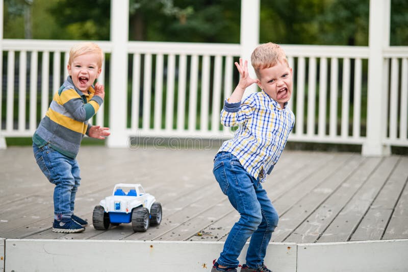 Two Boys Making Funny Faces and Playing Outdoors with Toy Car Stock ...