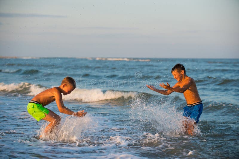 Two Boys Playing at the Beach with Water. Stock Image - Image of ...
