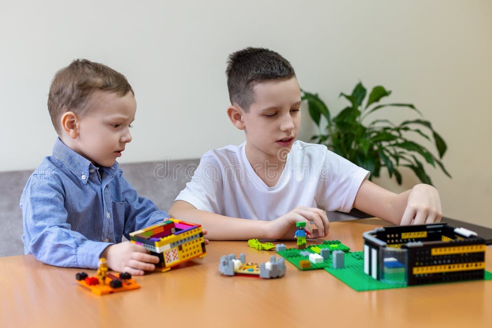 Two Boys Playing with Colorful Building Blocks at a Table, Constructing Creative Structures ...