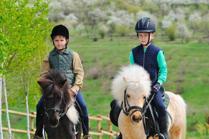 Boy and girl riding ponies stock photo. Image of male - 28644308