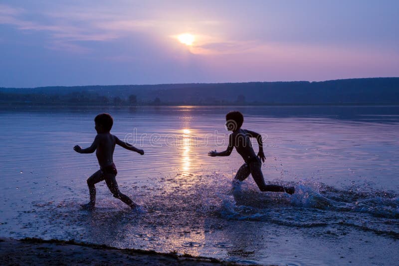 Two Boys Running on River S Beach Against Sunset Stock Photo - Image of ...