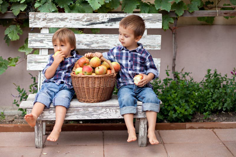 Two Boys, Sitting on a Bench, Eating Apples and Having Fun Stock Image ...