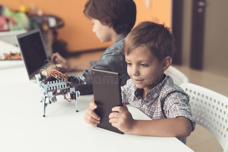 Two Boys are Sitting in the Workshop at the Table. One of Them Sits ...