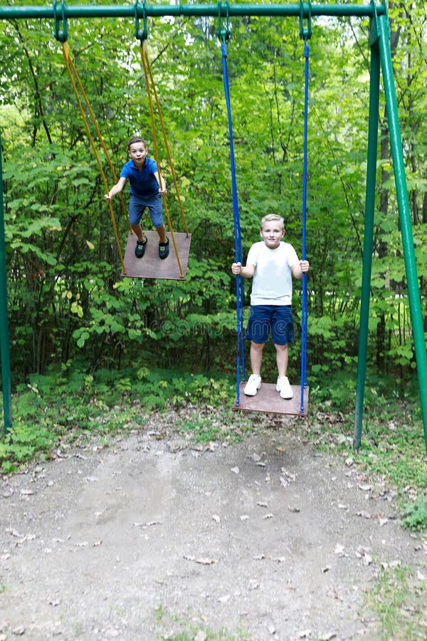Two boys swinging on swing stock photo. Image of leaves - 162049392