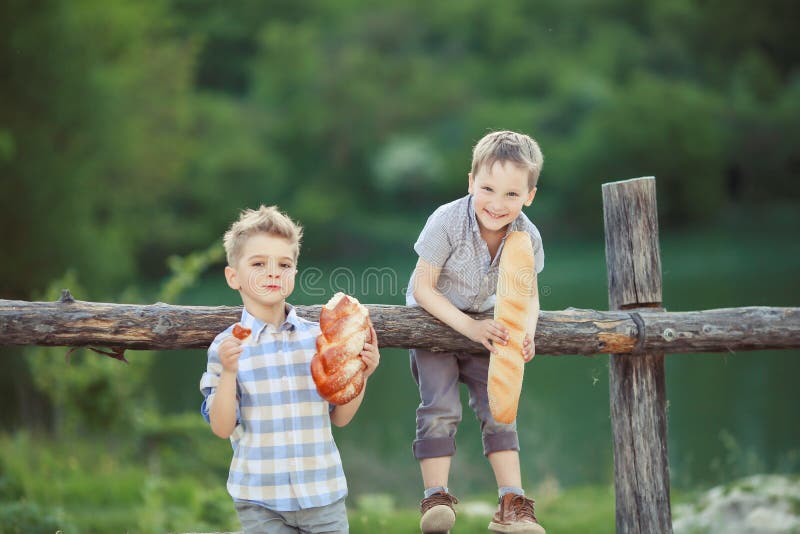 Two Brothers Eat Black Round Bread on a Wheat Field. Stock Photo ...