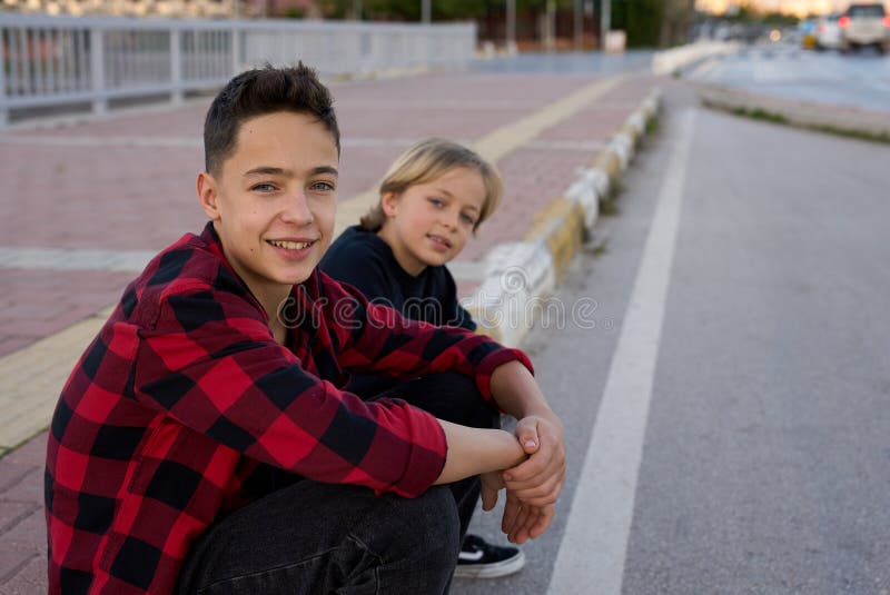Two Brothers Sitting Outside on a Sidewalk and Have Fun. Stock Image ...