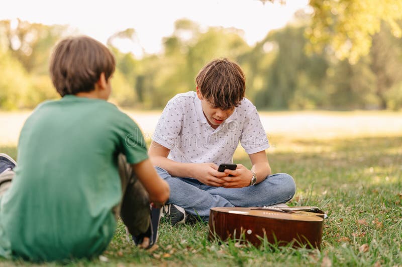Two Brothers are Spending Time in Park while Talking, Playing Phone and ...