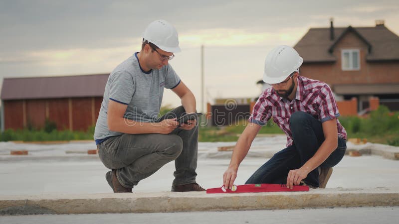 Two Builders Check the Accuracy of Building the Base of the Building ...