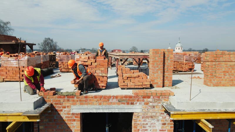 Two Builders Laying a Brick Wall on the Construction of a Multi-storey ...