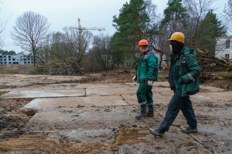 Two Builders in Orange Helmets are Walking through the Territory of the ...
