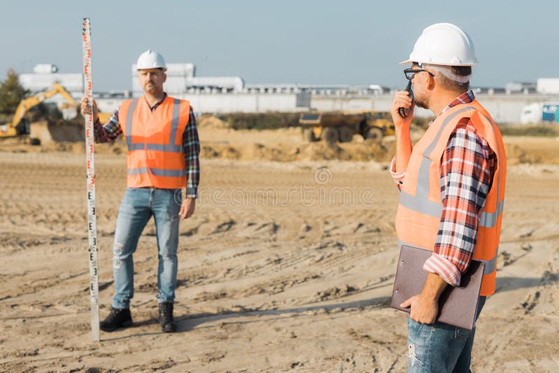 Builders in Orange Vests and Helmets Working on the Road Construction ...