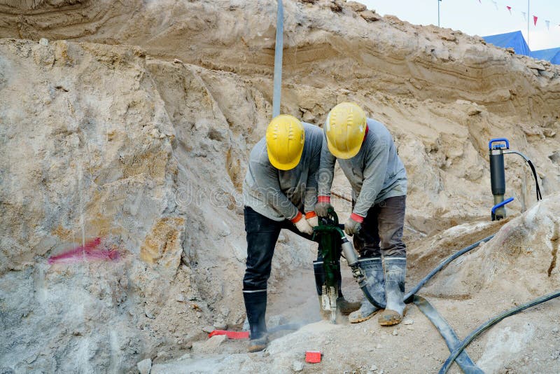 Two Builders Work Together with a Large Rock Drill To Break Apart in a ...