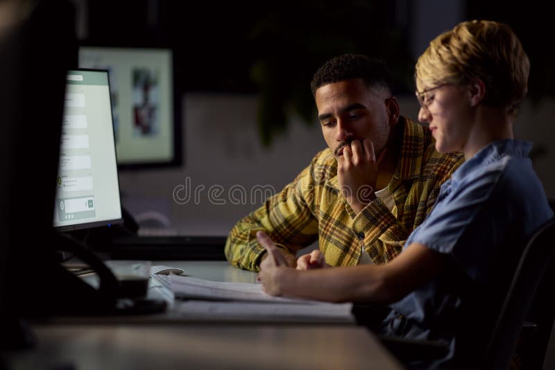 Two Business Colleagues at Desks in Office Working Late on Project ...
