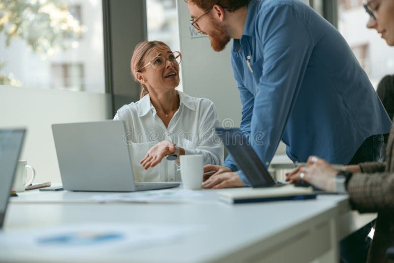 Two Business Colleagues Working Together on Project in Office while Use ...