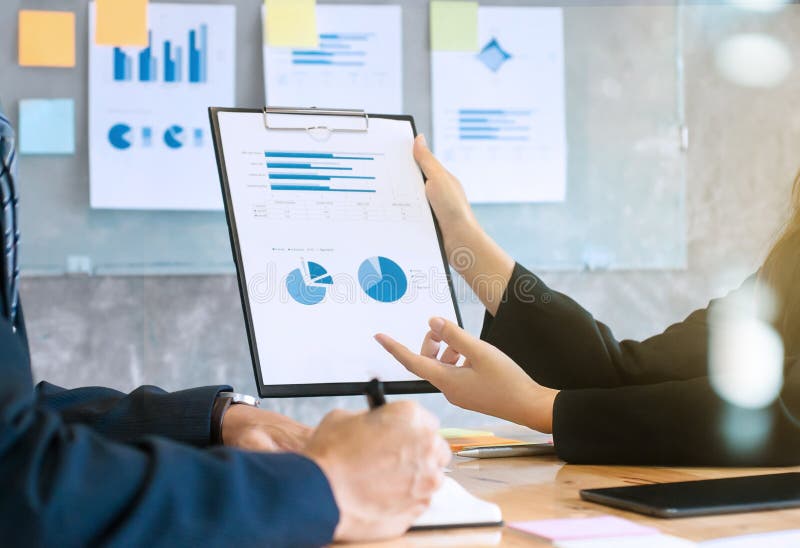 Two Business Executives Analyzing Data Paper on a Clipboard at Meeting ...
