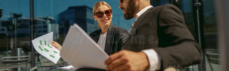 Two Business Partners Working with Documents Sitting Outside of Office ...