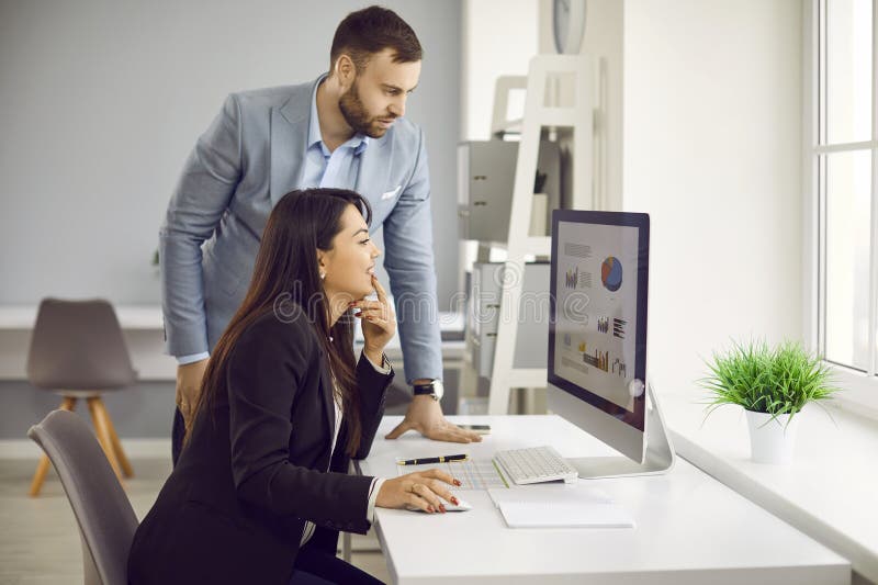 Two Business People Looking at Graphs and Charts on the Computer Screen ...