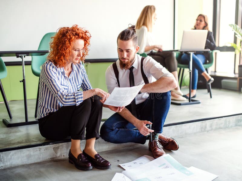 Two Business People Looking at Paper Documents in an Office, Talking ...