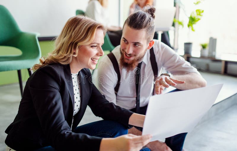 Two Business People Looking at Paper Documents in an Office, Talking ...