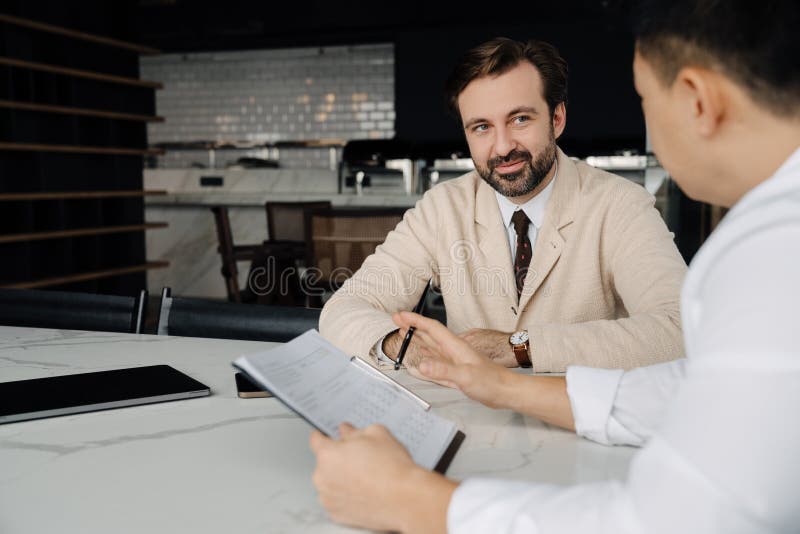Two Business People Sitting by Office Table and Discussing Project ...