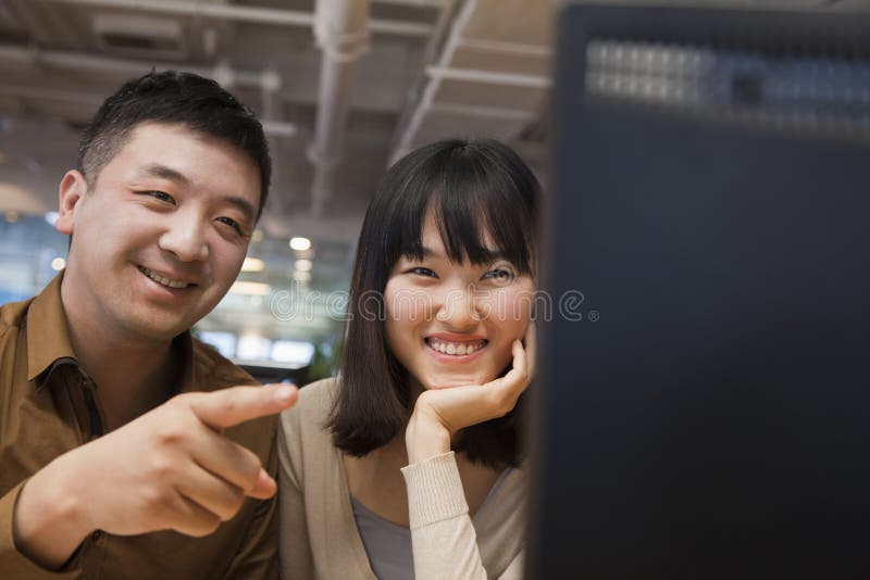 Two Business People Smiling and Looking at Computer in the Office Stock ...