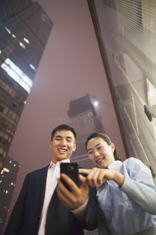 Two Business People Smiling and Looking at the Phone, Pointing ...