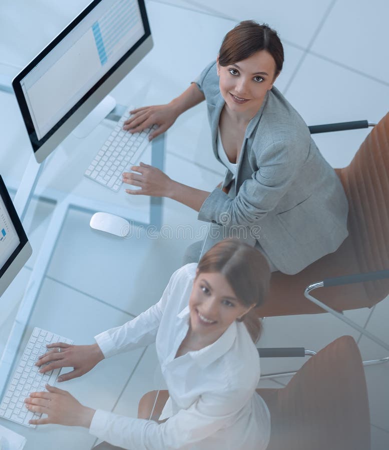 Two Business Women Sitting at Desk and Looking at Camera. Stock Photo ...