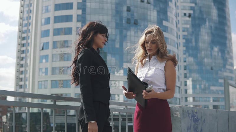 Two Business Women Talking and Looking at Documents in a Folder Stock ...