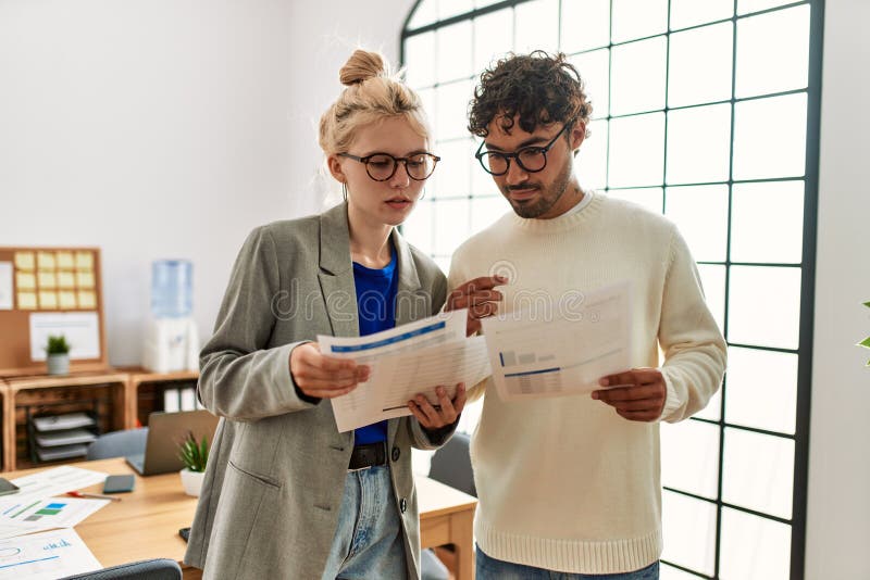 Two Business Workers Concentrated Reading Paperwork Standing at the ...