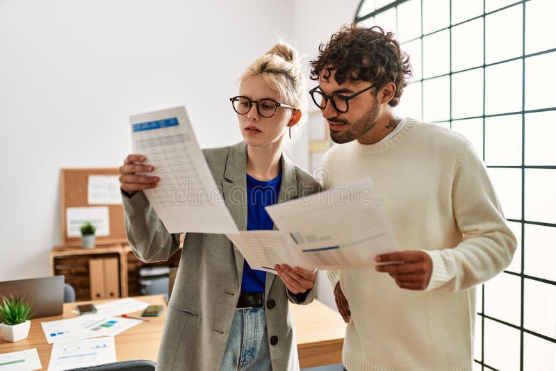 Two Business Workers Concentrated Reading Paperwork Standing at the ...